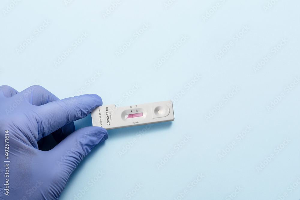 A gloved hand shows how a device to perform a sars covid 19 test at the ...