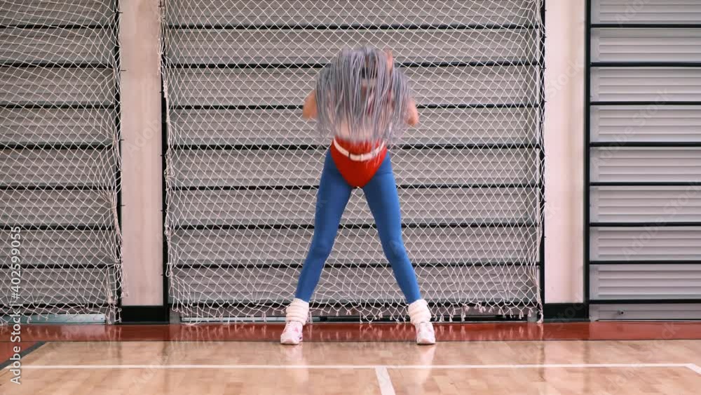 80s sporty retro style. Woman in blue leggings and red swimsuit doing ...