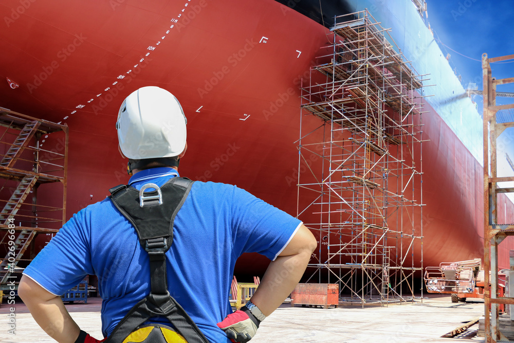 Worker wear safety belt and harness standing in factory on scaffolding ...