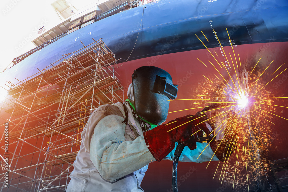 Welder worker welding ship repair of hull on cargo ship and scaffolding ...