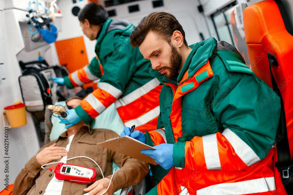 A paramedic woman in uniform puts on a ventilator with oxygen to help ...