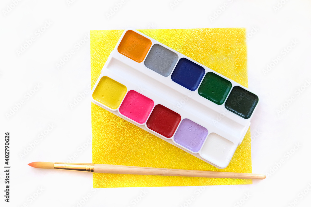 Art palette with paints and brush. water-color paint-box on yellow ...