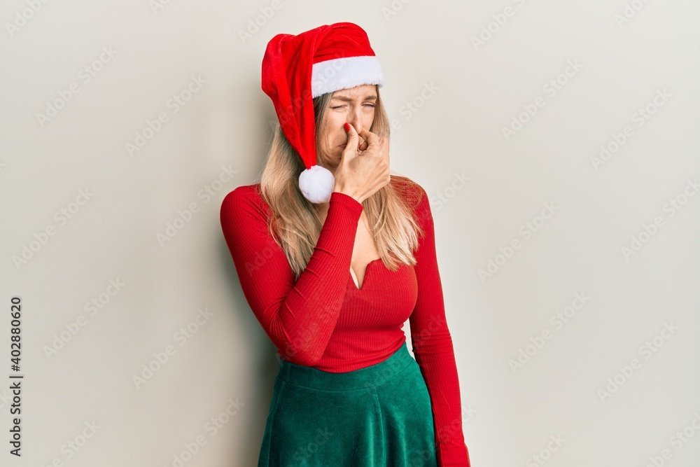 Beautiful caucasian woman wearing christmas costume and hat smelling ...