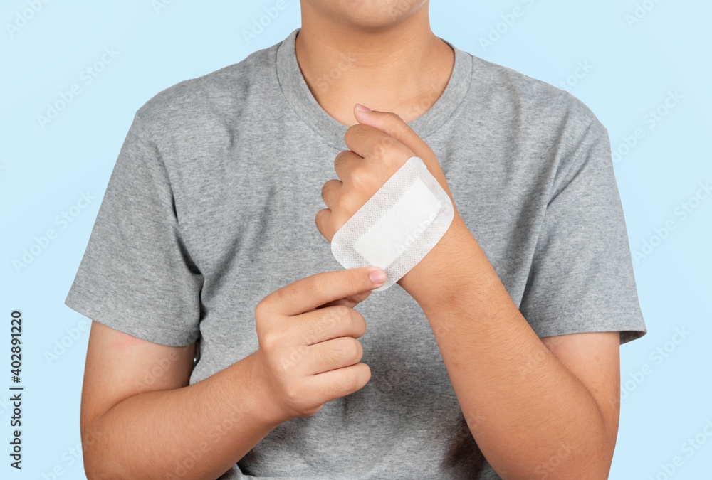 Boy putting adhesive bandage, plaster or band-aid on a cut hand ...