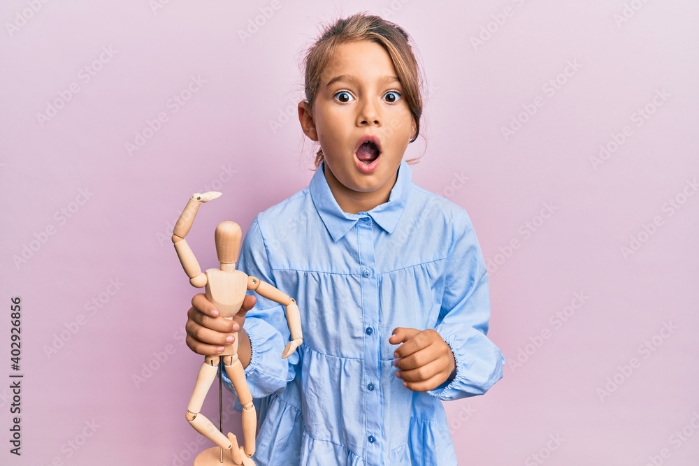 Little beautiful girl holding small wooden manikin scared and amazed ...