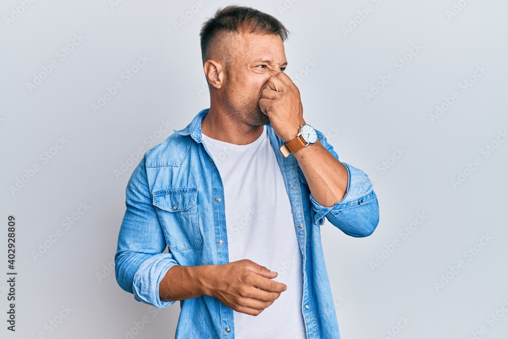 Handsome muscle man wearing casual denim jacket smelling something ...