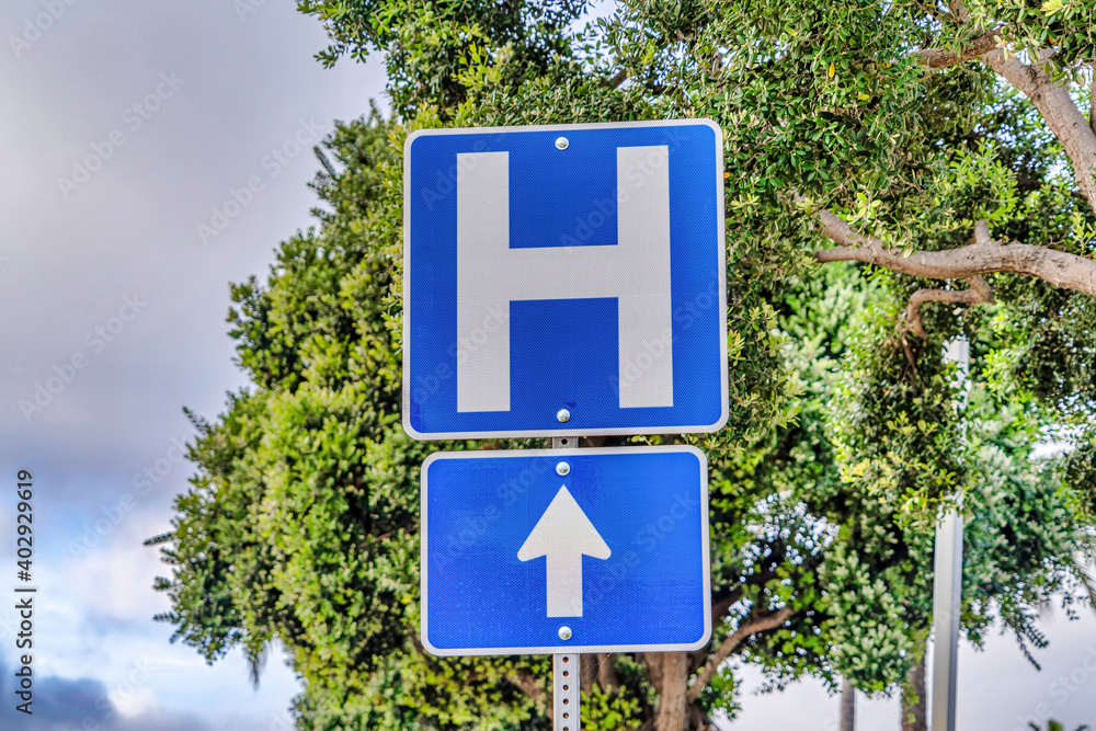 Road sign with tree and sky background with capital H for Hospital ...