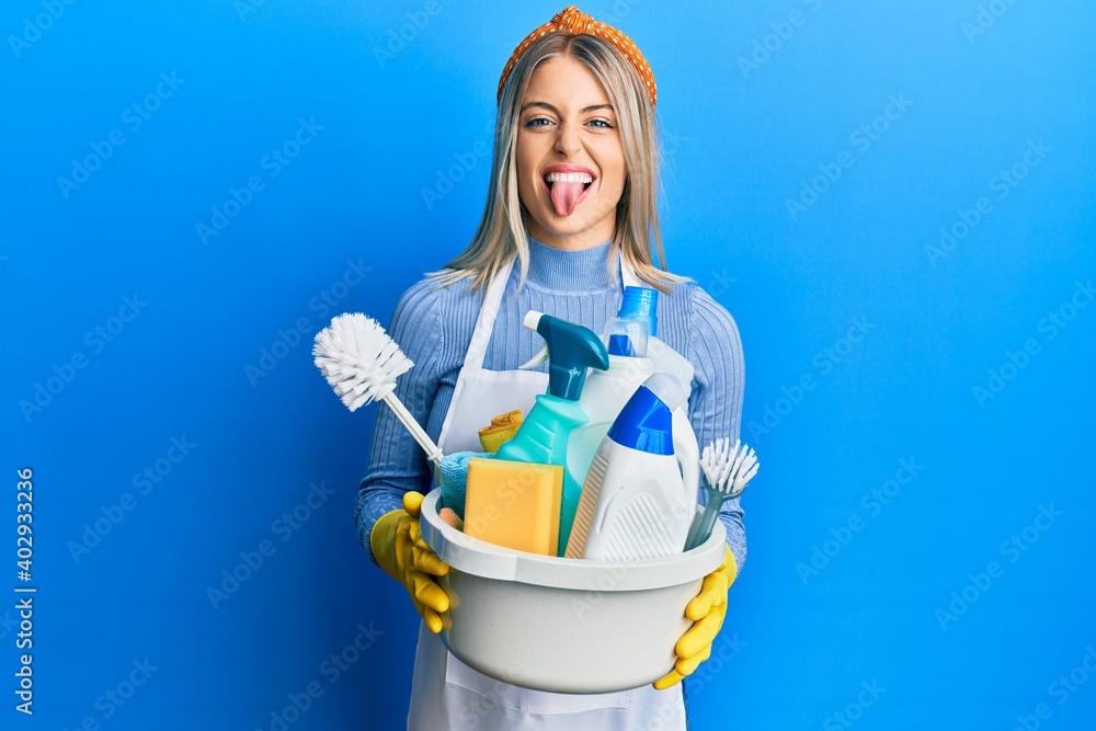 Foto de Beautiful blonde woman wearing cleaner apron holding cleaning ...