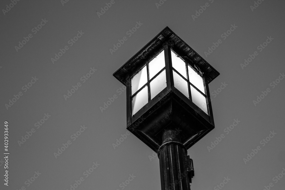Old fashioned lamp post illuminated against the night sky. Black and ...