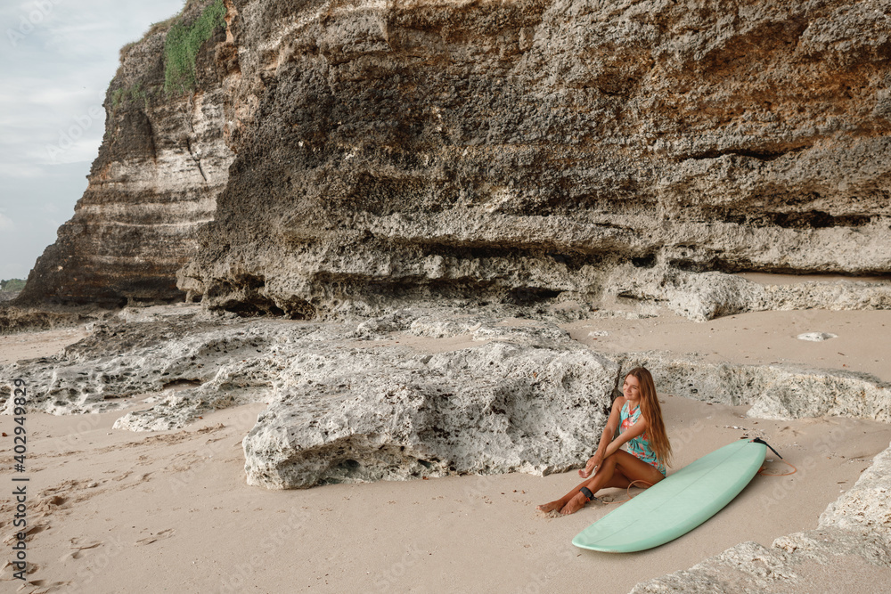 retty girl or sporty young surf woman watching sunset, sitting on the ...