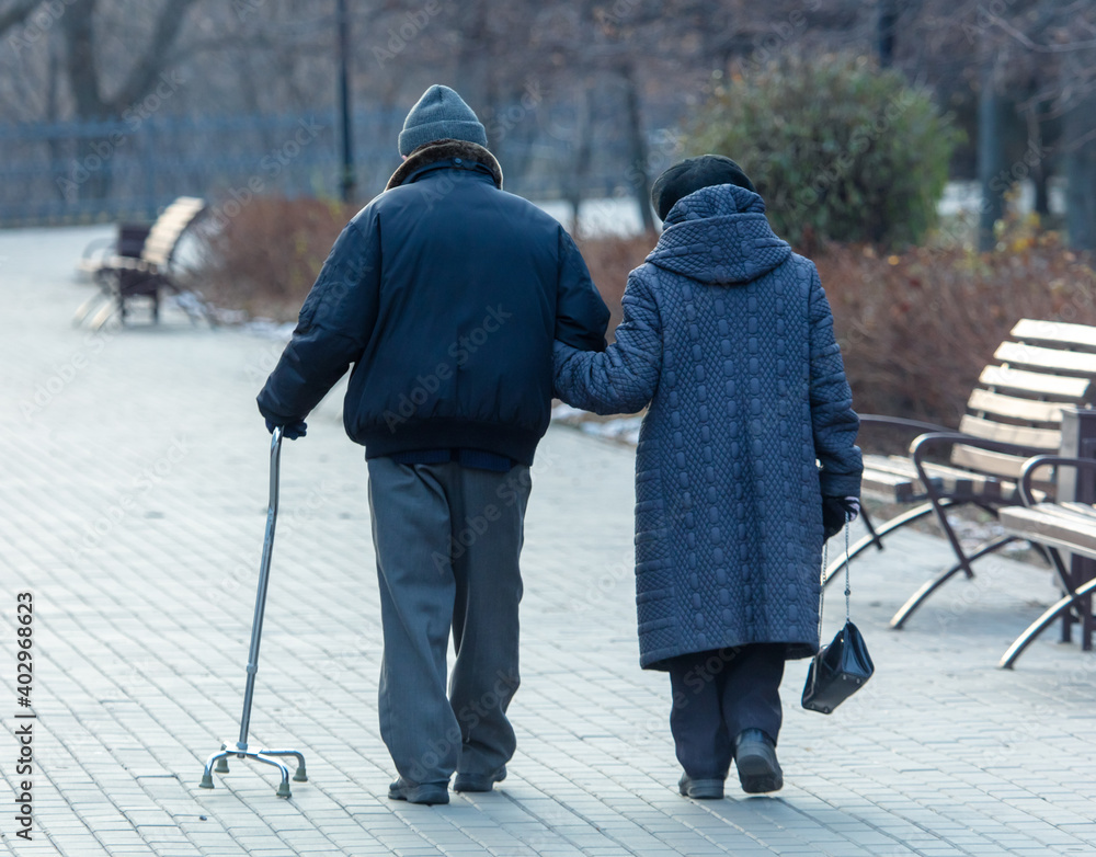 Grandpa leans on a cane while walking with grandmother Stock Photo ...