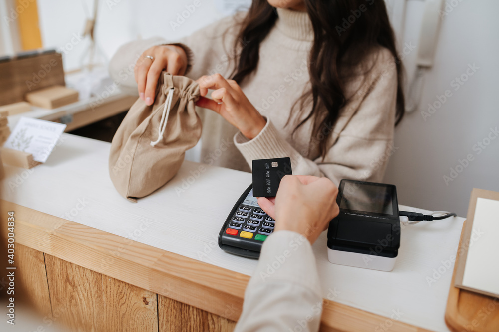 Shopkeeper behind stand with cash register, putting goods in a fabric ...