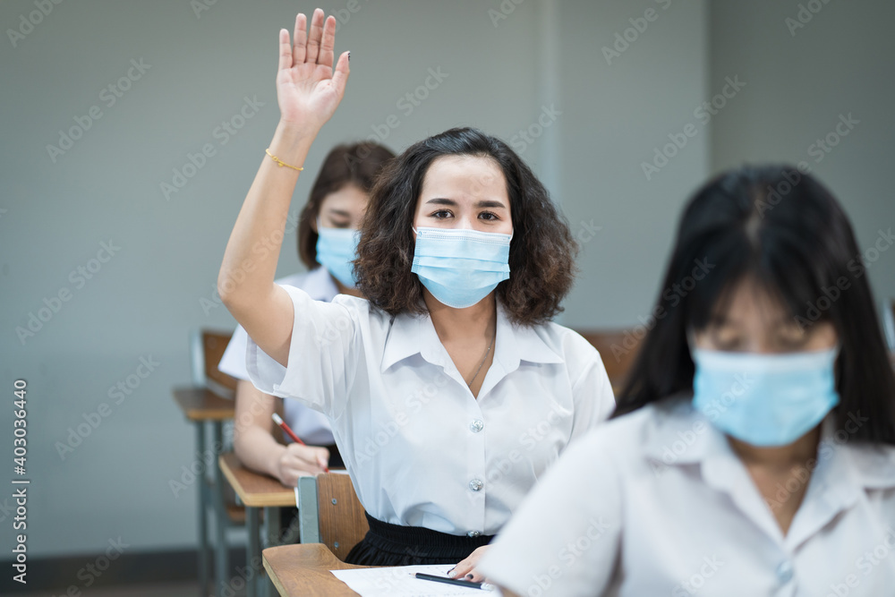 College students wear face mask study in classroom and raise hand to ...