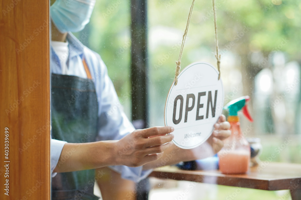 Waiter in protective mask turn store notice board sign at front door to ...