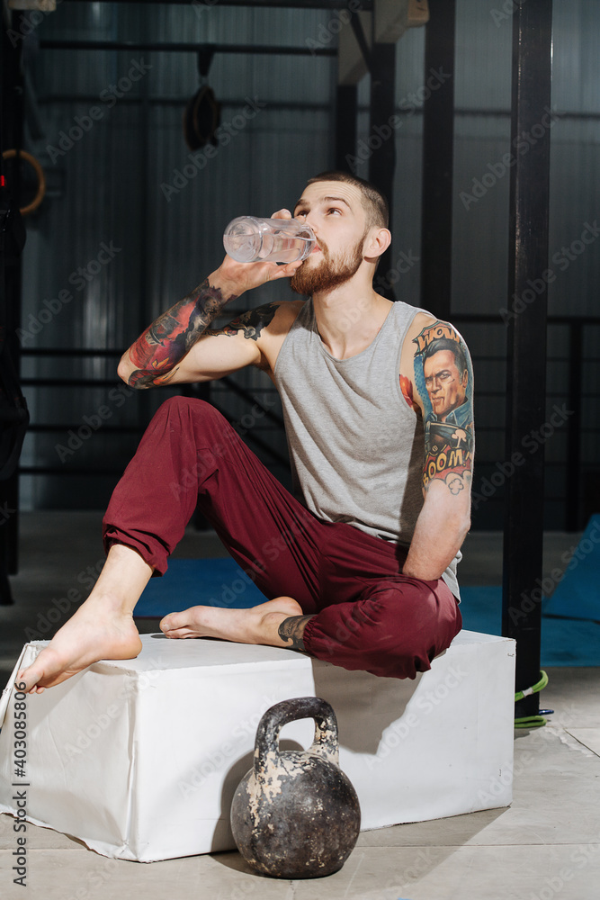 Thirsty armless young man drinking water, sitting on a pedestal next to ...