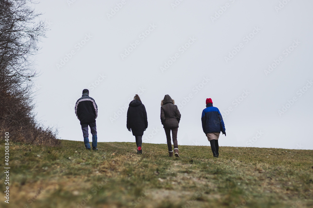 A group of people walk side by side through the countryside in cold ...