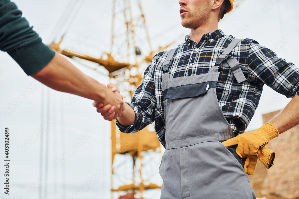 Making handshake. Two construction workers in uniform and safety ...