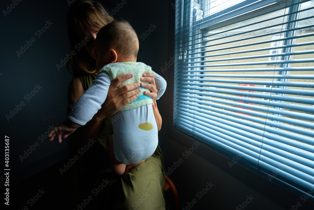 Young mother by window holding baby with soiled diaper Stock Photo ...