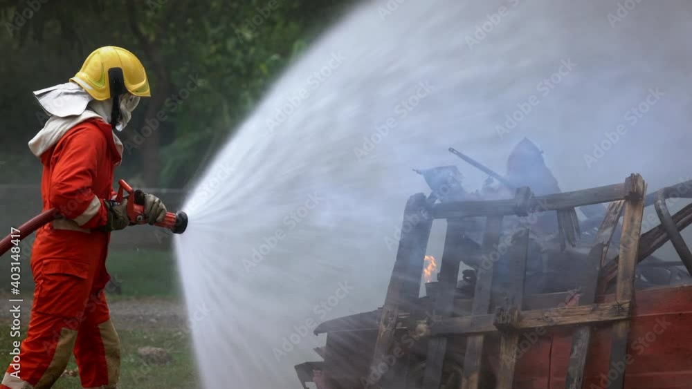 Brave firefighter in fire protection suit on safety rescue duty spray ...