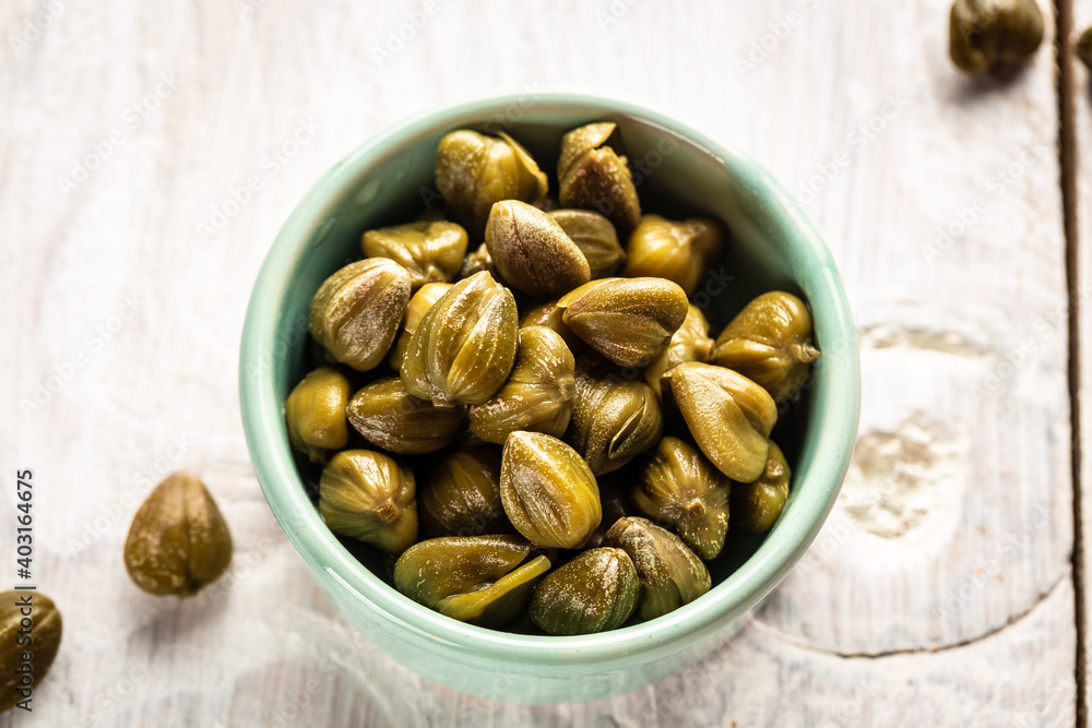 Marinated capers in a ceramic bowl. Edible flower buds of Capparis ...