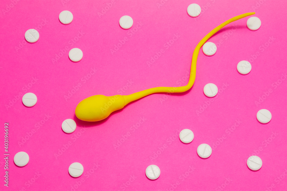 A medical magnified figure of a sperm cell lies on a pink polka dot ...