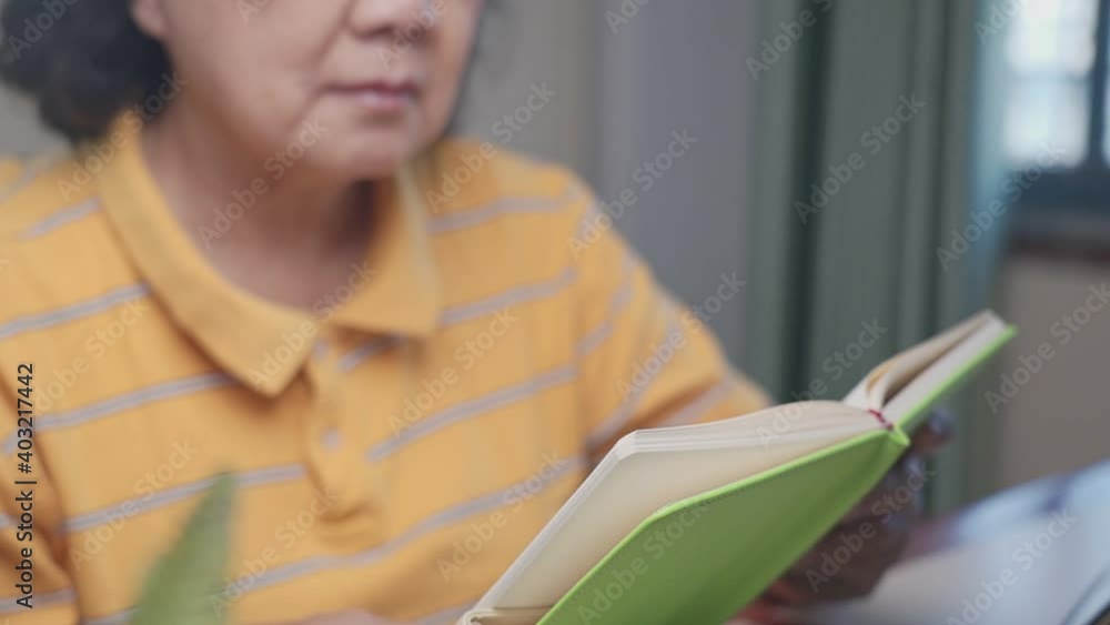 Old asian woman reads book at home desk, focusing concentrate while ...