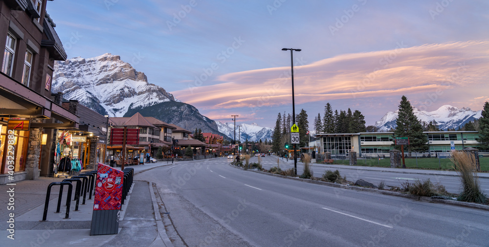 Street view of Banff Avenue in autumn evening. Snow capped Cascade ...