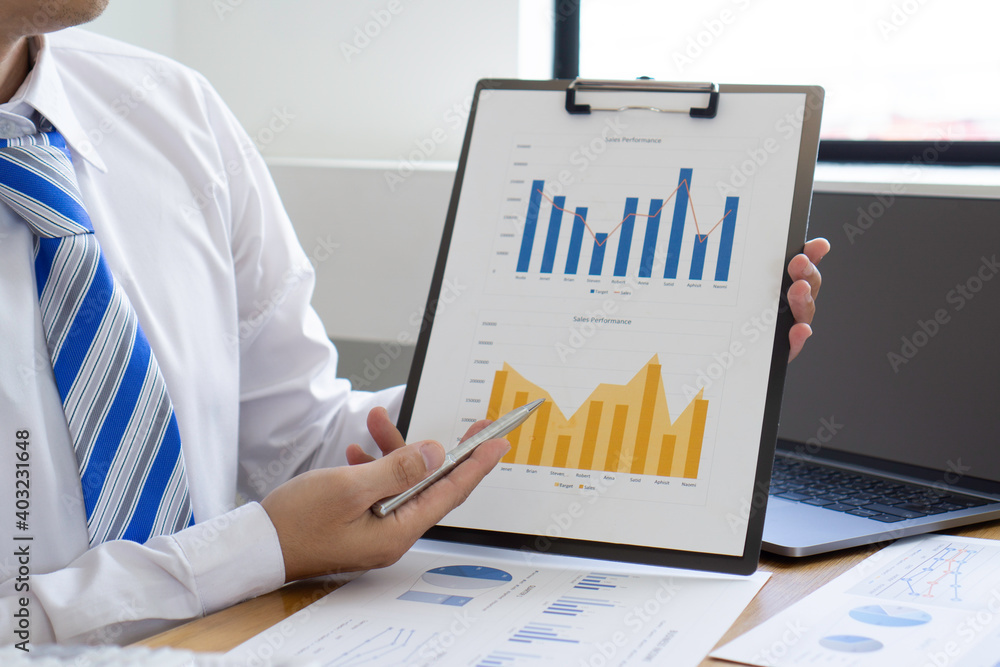 Asian finance staff is sitting at the table. The hand is holding a pen ...