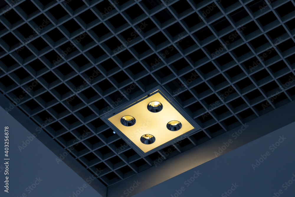 Square lighting fixture with four lamps on the ceiling of an commercial ...