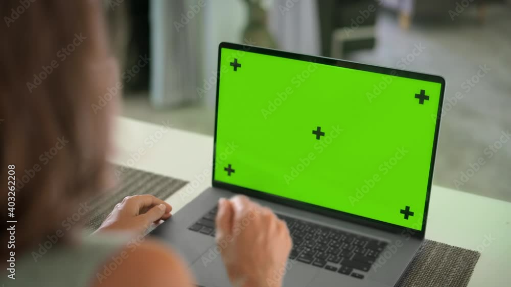 Girl working on laptop with Mock up green screen on the table in modern ...