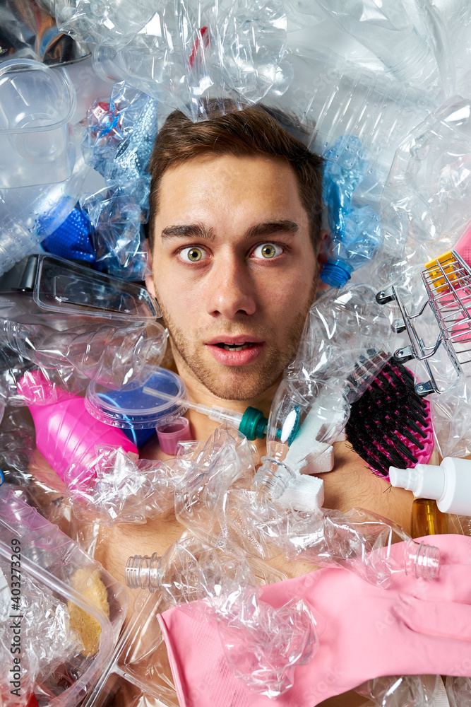 man drowning under plastic recipients pile, garbage, used packs filling ...