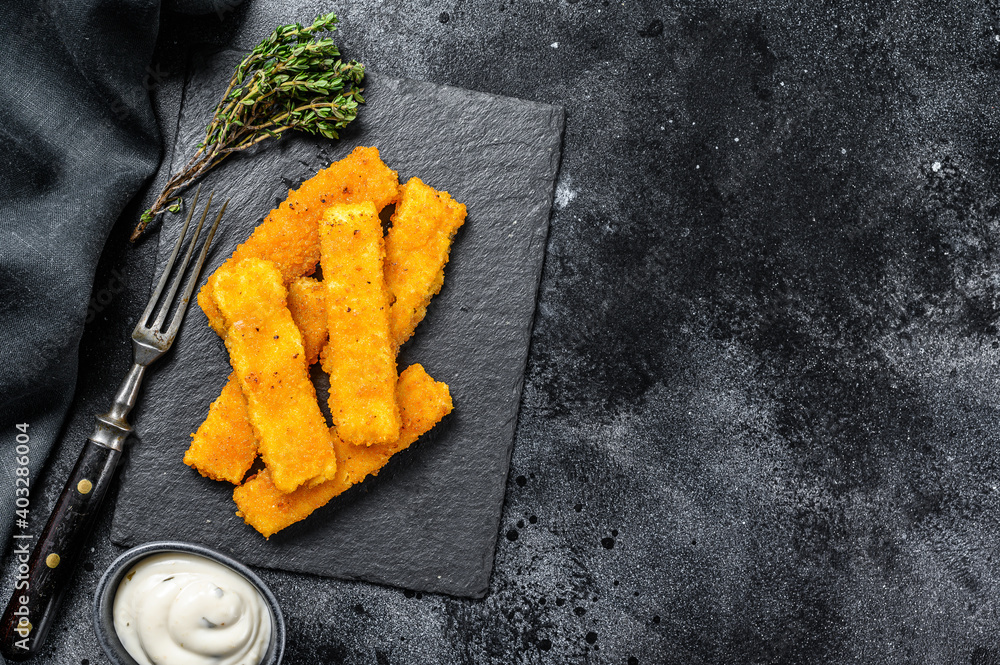 Oven baked crumbed fish sticks made from white fish. Black background ...