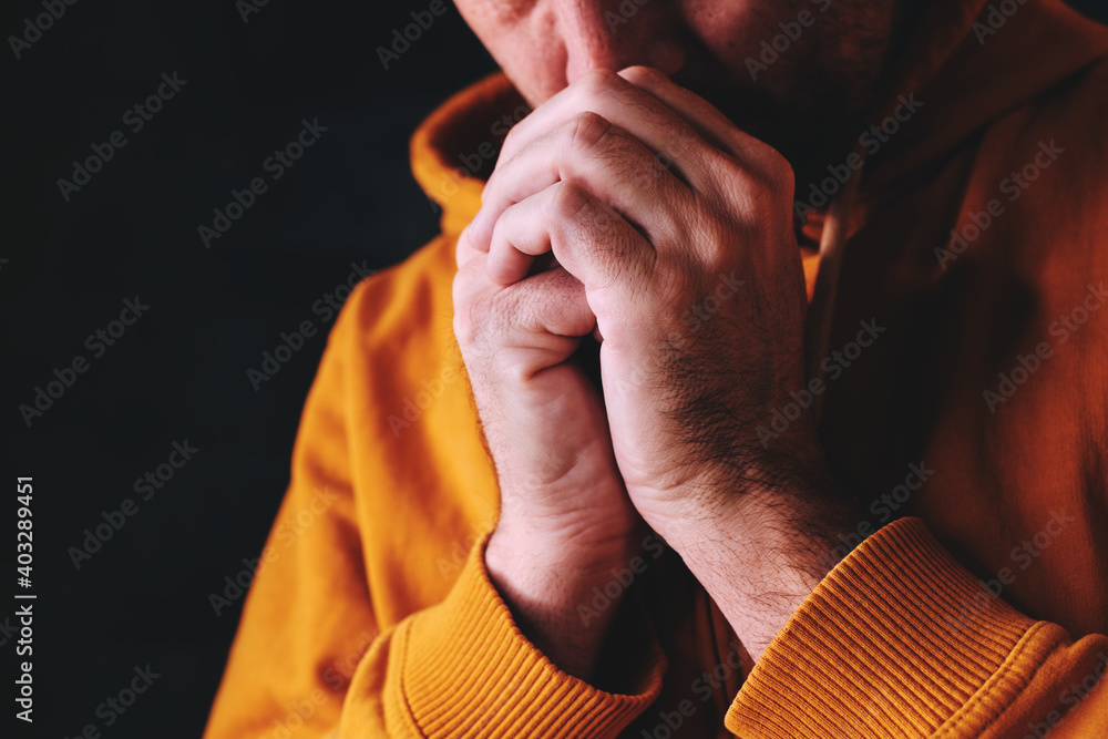 Christian man praying to God in dark room with clasped hands Stock ...