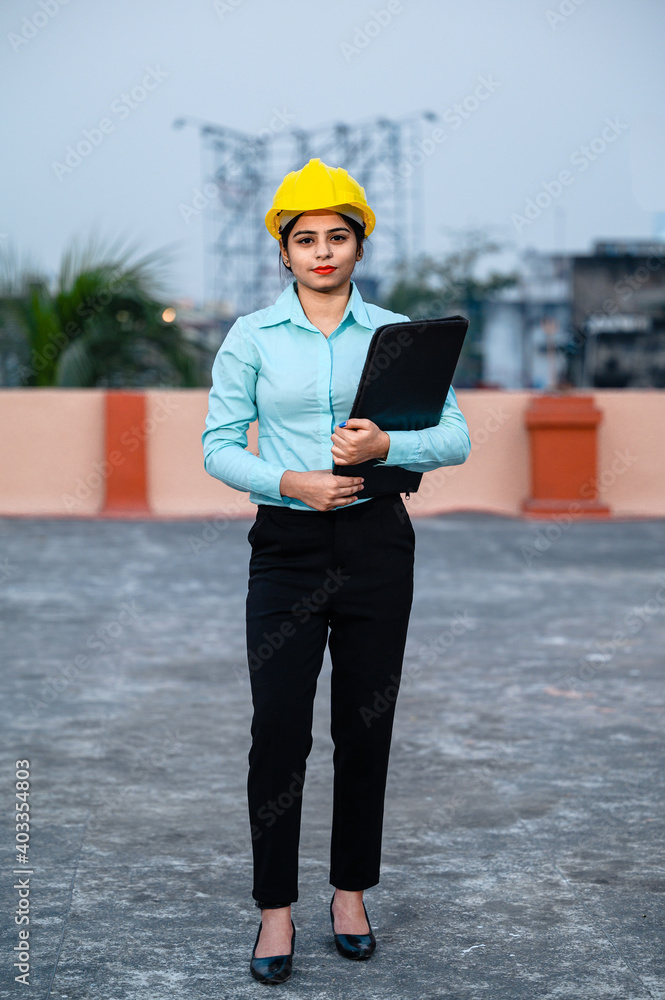 Full length portrait of beautiful female engineer wearing a protective ...