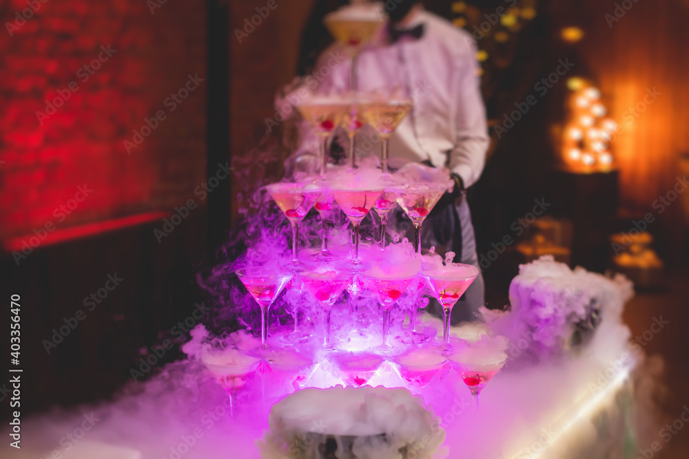 Glasses with alcoholic beverages in the pyramid, filling and pouring ...