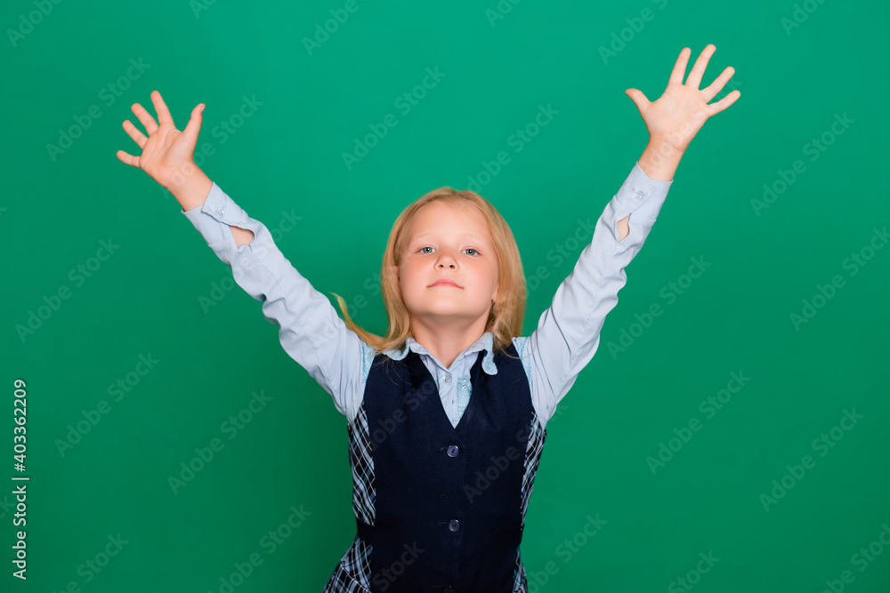 Girl in school uniform stands with raised arms up isolated on a green ...