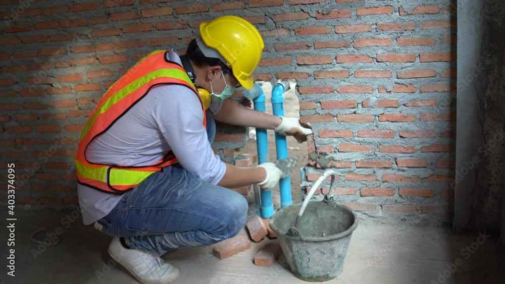 asian bricklayer worker installing brick masonry Closing pvc pipe for ...