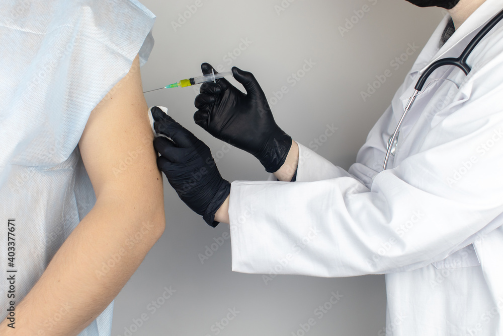 Infectious disease doctor gives the patient a medical vaccination in ...
