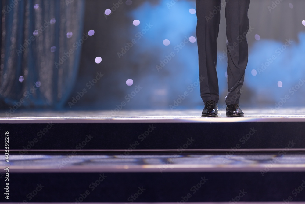 male feet in black shoes stand on a staircase in the theater hall ...