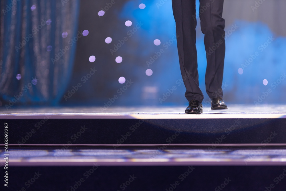 male feet in black shoes stand on a staircase in the theater hall ...