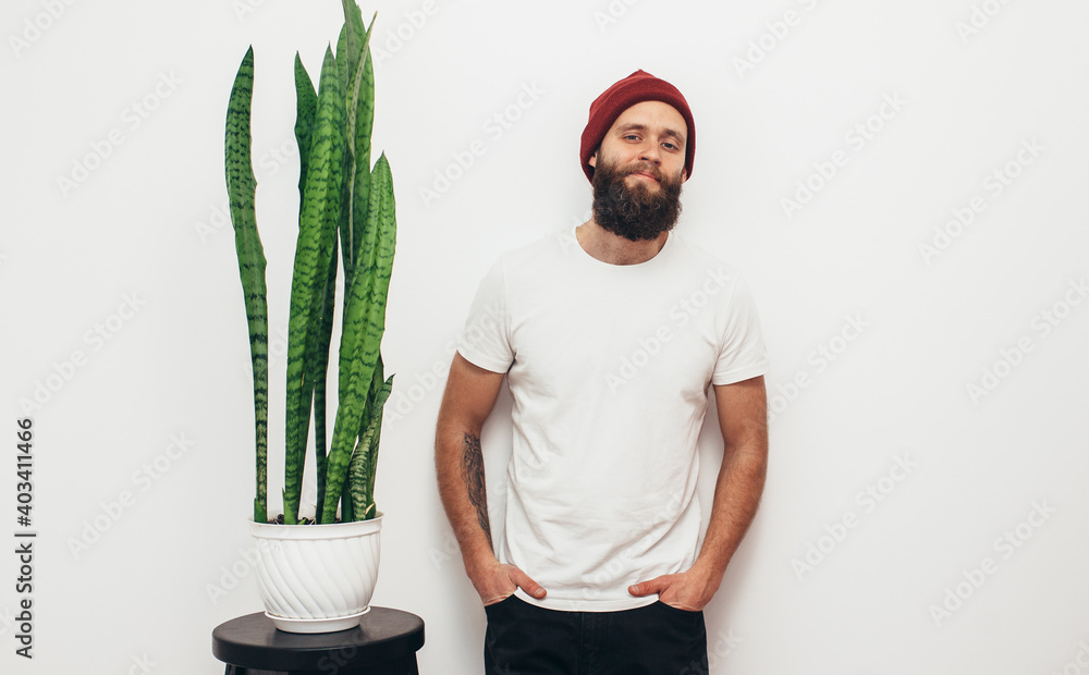 Young bearded hipster guy with a pot in his hands wearing white blank t ...