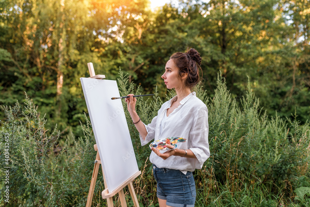 girl artist, woman paints picture landscape, summer forest, denim ...