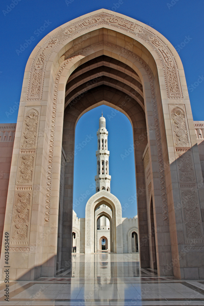 Fototapeta Tall white minaret towers over the structures and arches of ...