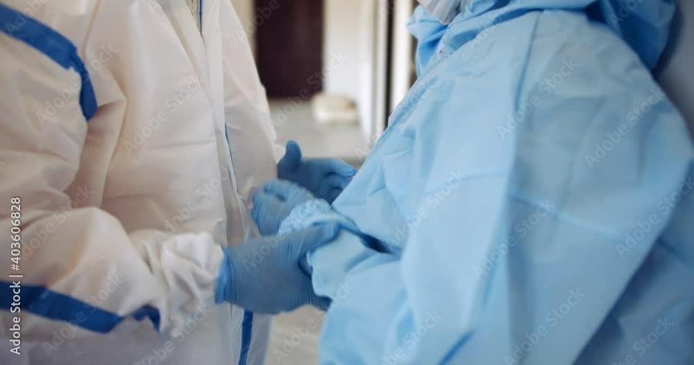 Two women doctors nurses wearing full body PPE suits indoors at a ...