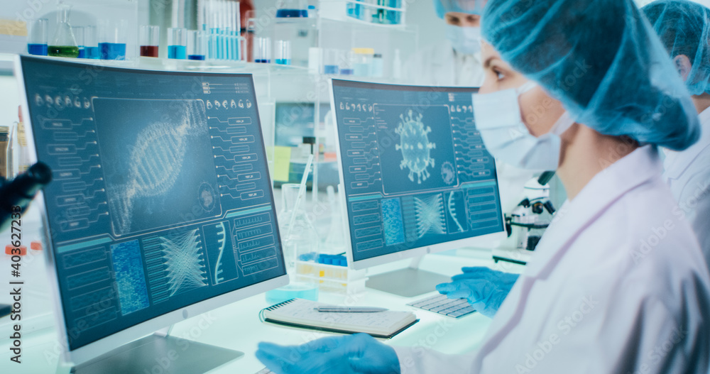 Two female scientists sitting in front of computer screens with ...