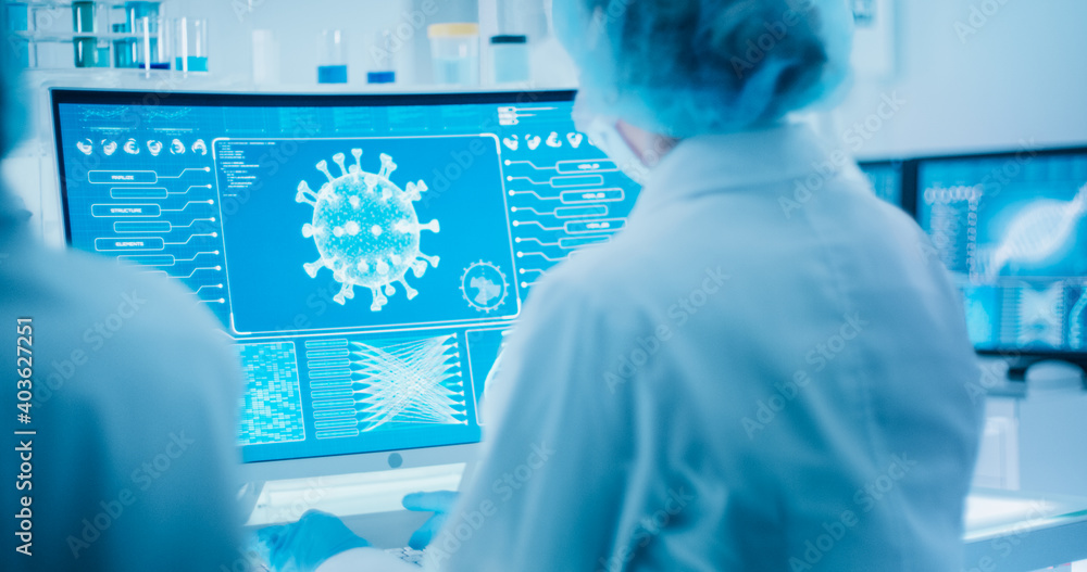 Two female scientists sitting in front of computer screens with ...