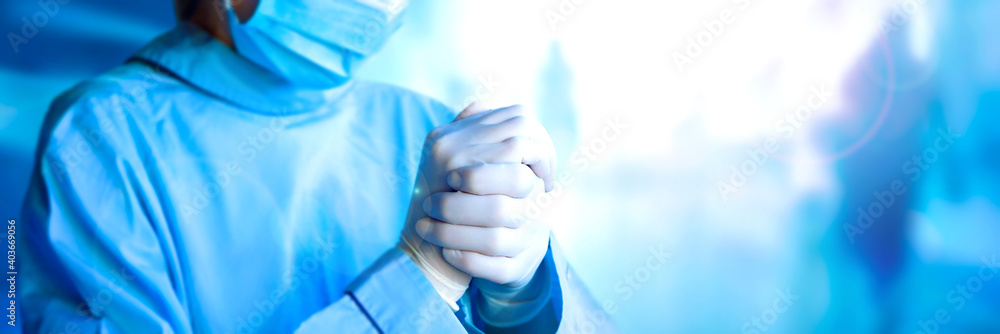 Frontline tired young female doctor putting on sterile gloves. Wearing ...
