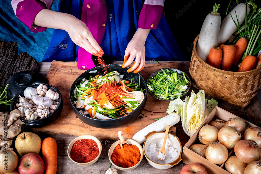 Korean woman is wearing a traditional hanbok, she making Kimchi which ...