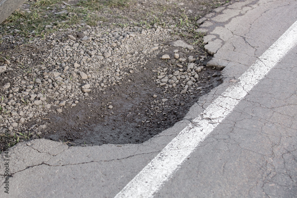 pothole with cracks tarmak road with white markings solid line, pit on ...