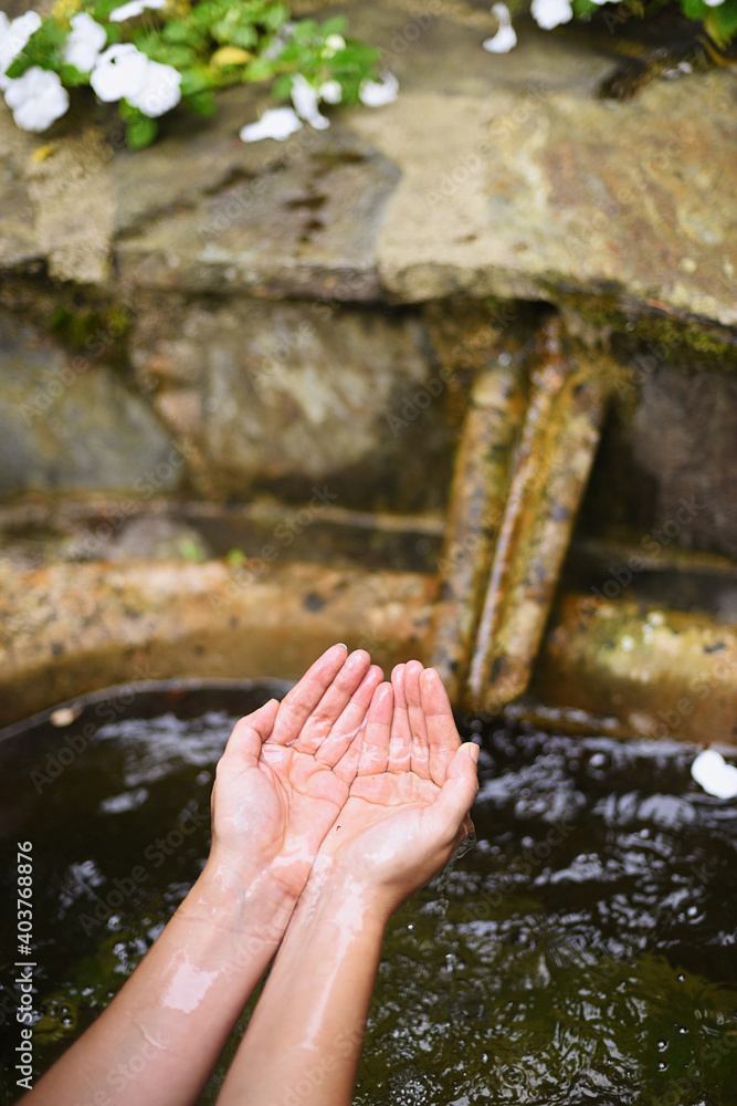 Women's hands picking up clear water from a fountain to refresh ...